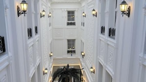 Um hall imponente com paredes brancas, molduras ornamentadas e teto de vidro.