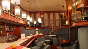 Uma área de bar com várias mesas, cadeiras e uma escada.