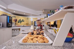 Uma área de buffet com diversos doces e uma máquina de café.