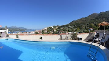 Piscina com vista para uma cidade situada no morro e montanhas ao fundo.