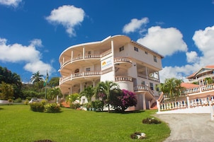 Um hotel de vários andares com fachada branca, varandas e um gramado bem cuidado.