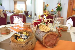 Mesa de jantar com arranjo rústico, com um tronco e flores secas.