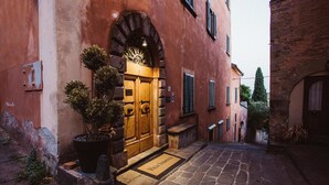 Uma rua de paralelepípedos estreita que leva a um edifício com porta de madeira e um pequeno vaso de planta.