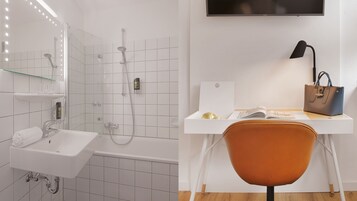 Casa de banho moderna com chuveiro, lavatório e secretária com cadeira.