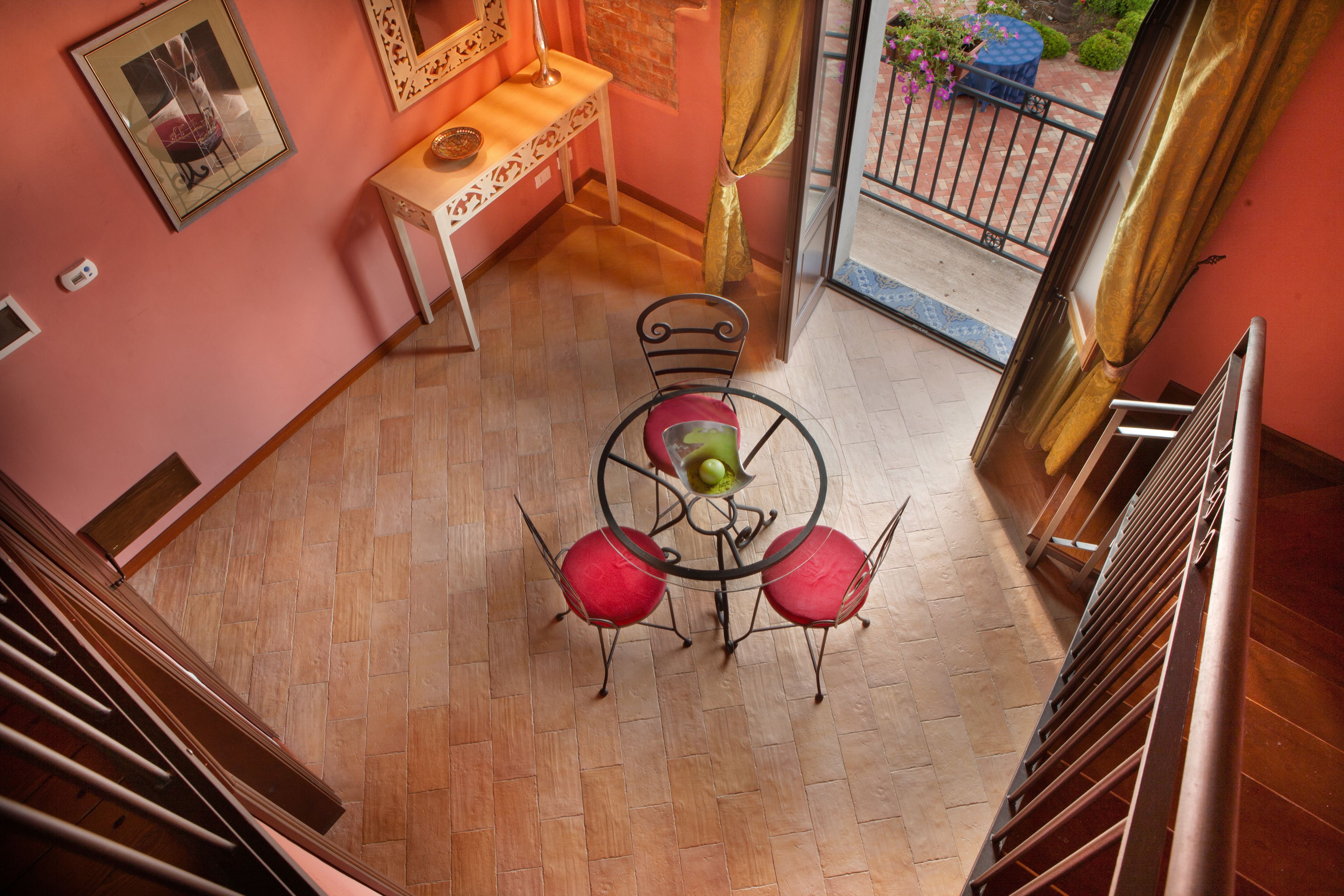 Uma escadaria leva a uma varanda com mesa, cadeiras e um banco, oferecendo vista para o exterior.