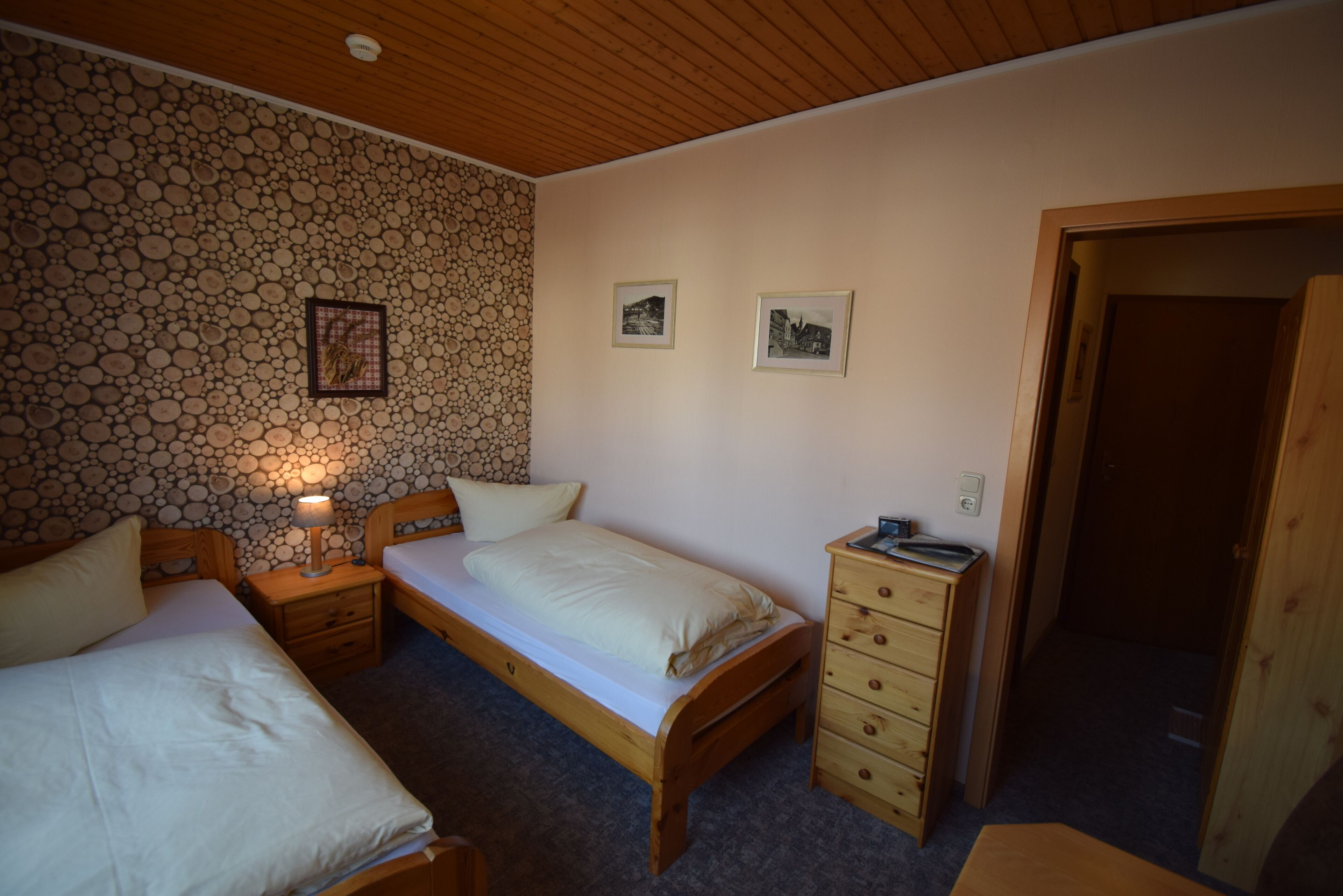 Quarto com duas camas, uma cômoda e parede com textura de pedra.