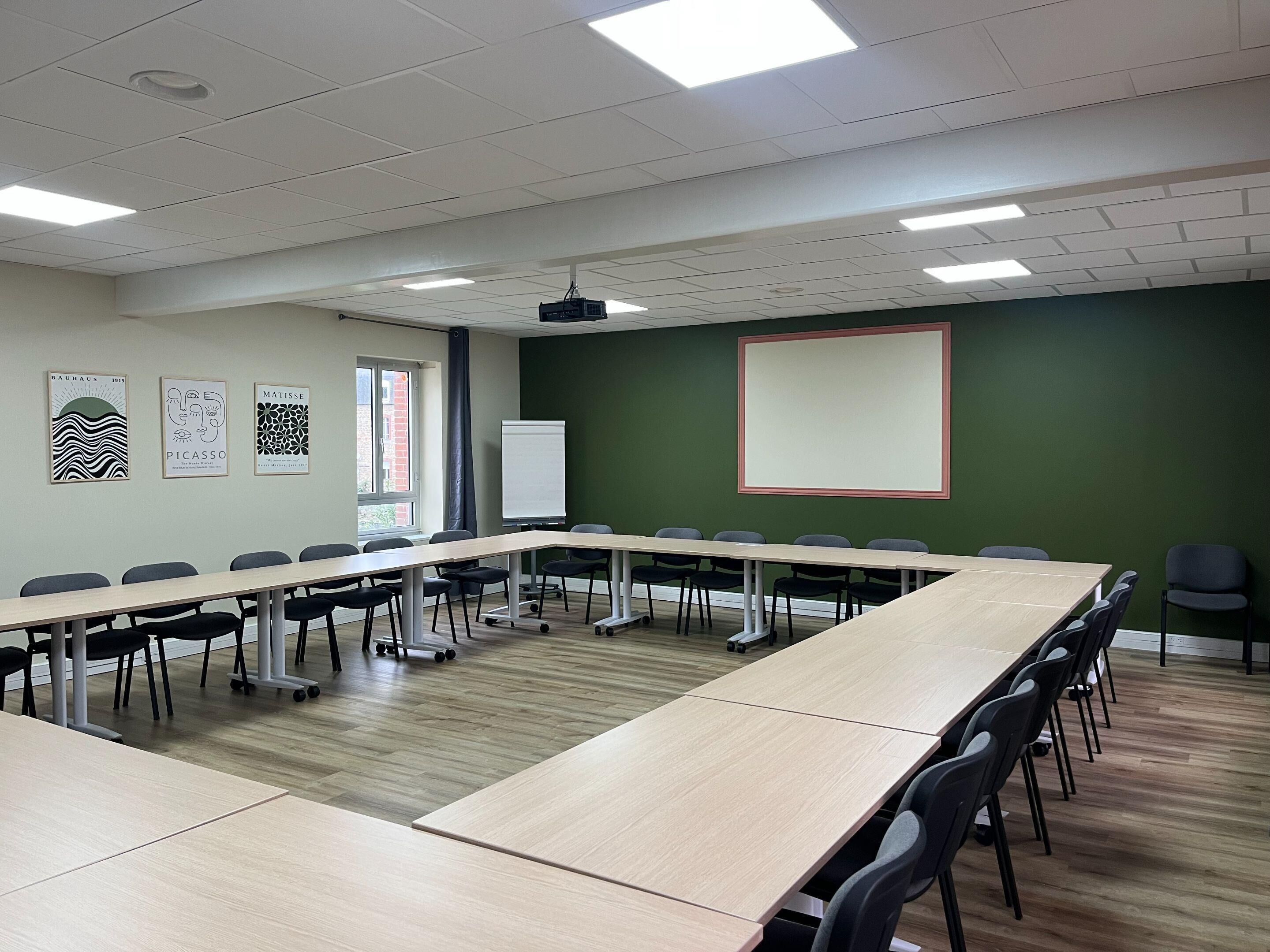 Uma sala de conferência com uma mesa comprida, cadeiras, um quadro branco e obras de arte nas paredes.