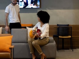 Uma sala de estar com sofá, televisão e poltrona.