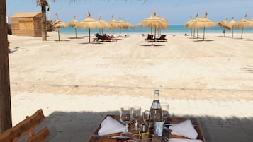 Praia de areia branca, espreguiçadeiras, guarda-sóis de praia