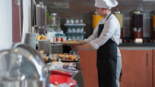 Um chef servindo comida em uma cozinha com sistema de buffet.
