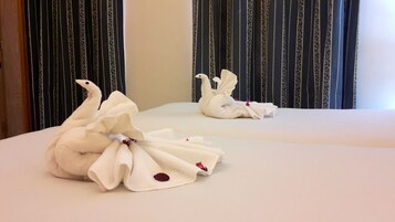 Quarto de hotel com duas camas, cada uma decorada com uma toalha em forma de cisne branco.