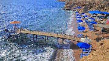 Uma praia privada, espreguiçadeiras, guarda-sóis de praia