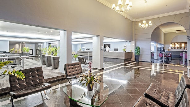 Um hall amplo com balcão de recepção, áreas de estar e um lustre moderno.