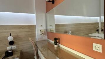 Casa de banho moderna com toucador, espelho e uma pequena planta.