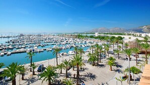 Marina com vários barcos atracados, cercada por palmeiras e um céu azul e límpido.