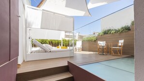 Uma área externa moderna com piscina, espreguiçadeira e espaço de estar com cadeiras e mesa.