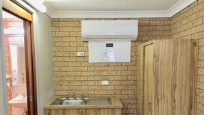 Uma cozinha compacta com pia, um pequeno frigorífico e ar condicionado integrado.