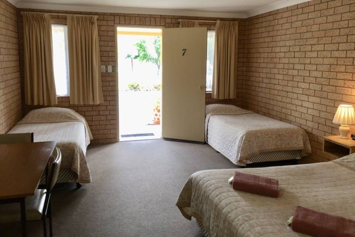 Quarto com duas camas de solteiro, uma escrivaninha e uma cadeira.