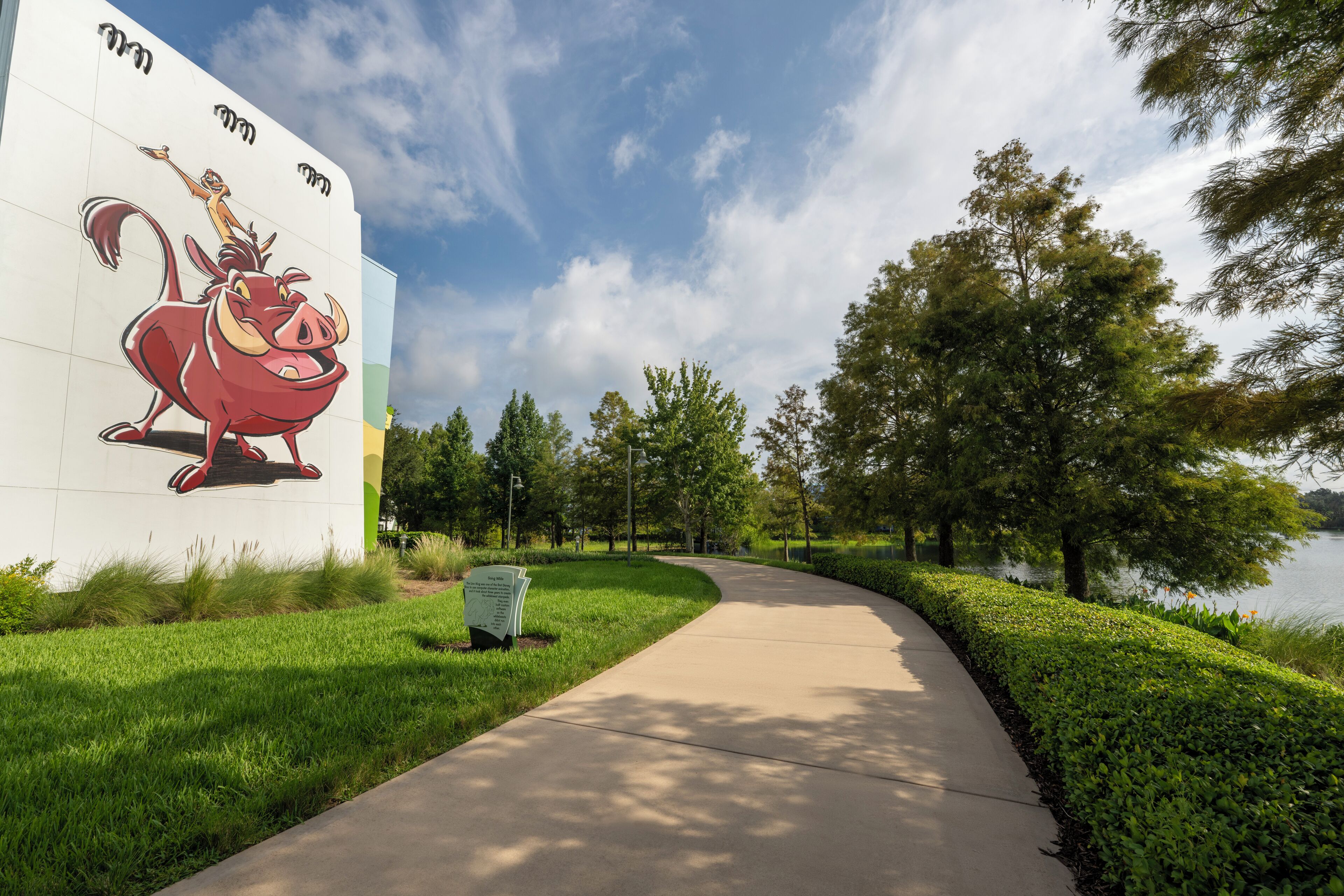 Uma passarela ao lado de um lago, com um mural de um touro de desenho animado em um edifício.