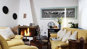 Uma sala de estar com dois sofás amarelos, uma lareira e uma parede com obras de arte emolduradas.