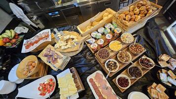 Uma mesa de buffet com diversas opções de comida, incluindo frutas, queijos, carnes e doces.
