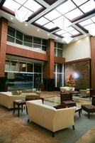 Um hall amplo com teto alto, janelas grandes e área de estar com sofás e mesas.