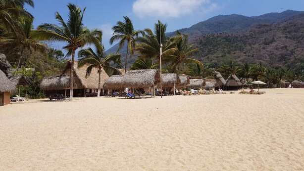 Na praia, barracas de praia de cortesia, espreguiçadeiras, guarda-sóis 