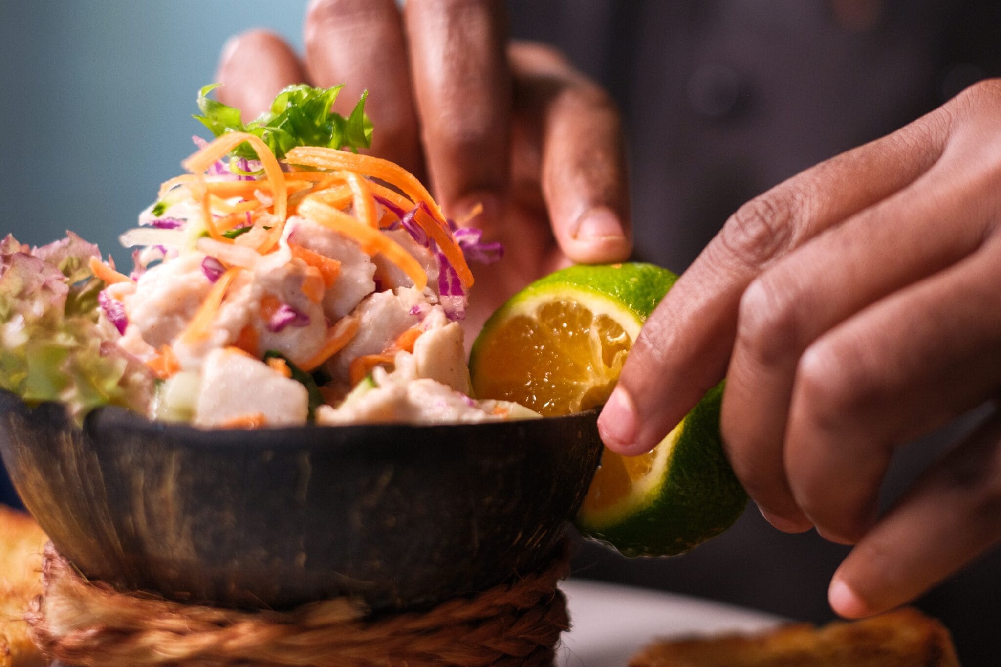 Uma salada com cenoura ralada e alface, sendo segurada por mãos.