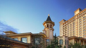 Um hotel com uma torre central, um edifício grande com várias varandas e estilo arquitetônico clássico.