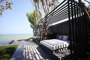 Quarto ao ar livre moderno com cama, área de estar e vista para o mar.