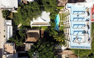 Vista aérea de um hotel com piscina, vários edifícios e vegetação ao redor.