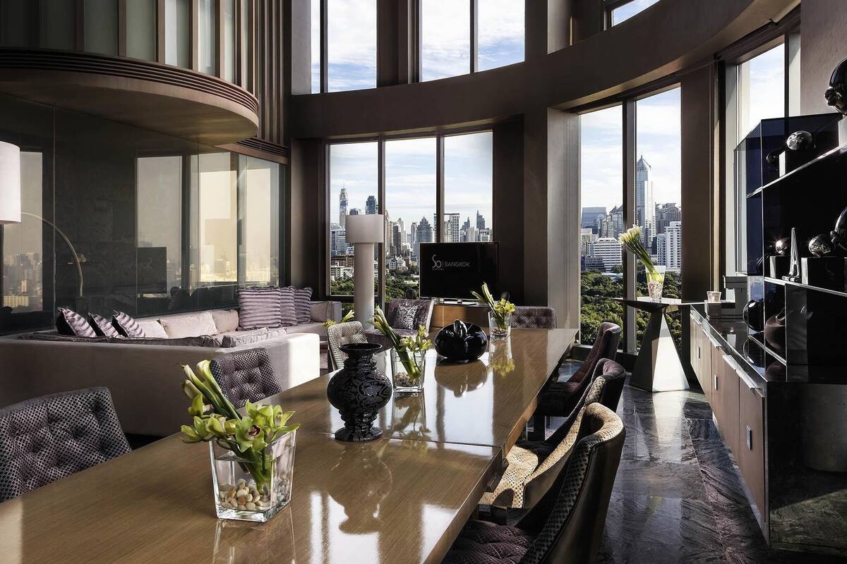 Quarto de hotel moderno com uma grande mesa de jantar, assentos e vista para a cidade.