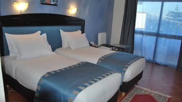 Uma cama de casal com cabeceira, duas mesas de cabeceira e uma janela com cortinas.