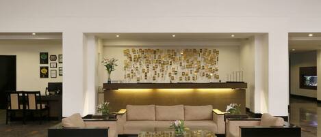 Um lobby moderno com um conjunto de sofás, uma mesa de centro e uma parede com quadros.