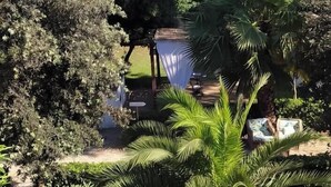 Um jardim com diversas plantas e uma construção ao fundo.