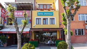 Hotel com fachada amarela, entrada visível e placa indicando que oferece cozinha chinesa e coreana.