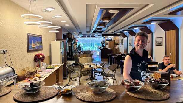 Interior moderno de restaurante com buffet, mobiliário de madeira e vista para a cidade através da janela.