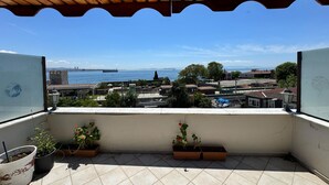 Varanda com vista para o mar, plantas em vasos e chão de azulejos.