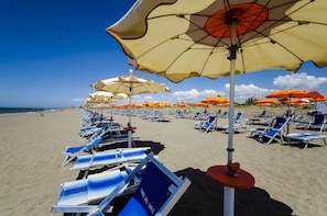 Uma praia com fileiras de espreguiçadeiras e guarda-sóis.