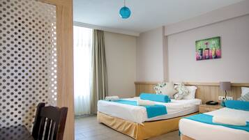 Quarto de hotel com duas camas, cabeceira de madeira, mesa de jantar e um elemento decorativo na parede.