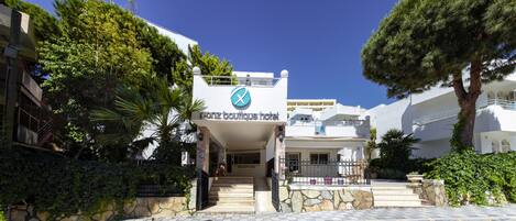 Entrada do Hotel Boutique Conrad, com uma escadaria de pedra, área de recepção e vegetação exuberante.
