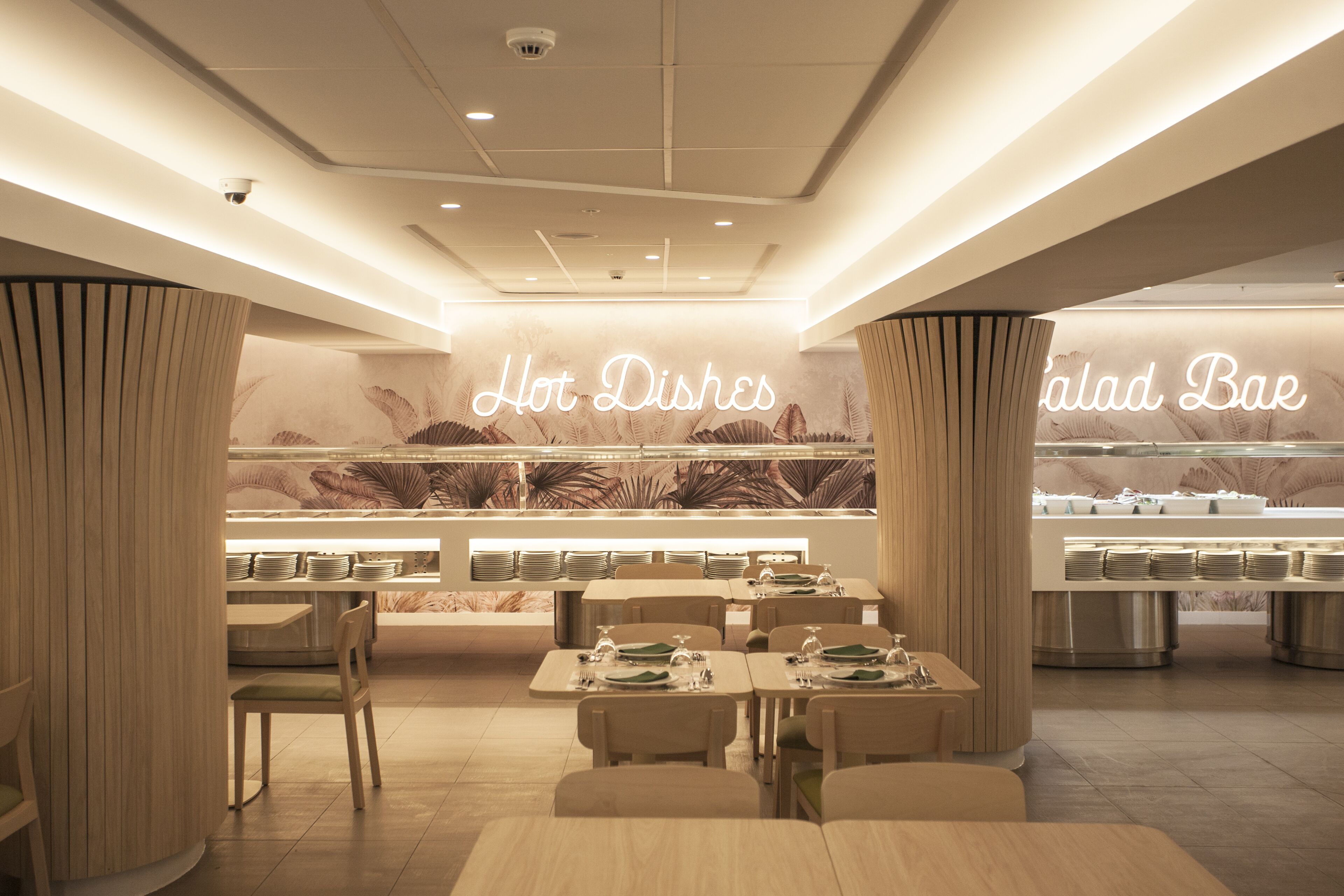 Um restaurante com um letreiro que diz 'Hot Dishes', cadeiras de madeira e uma área de buffet.