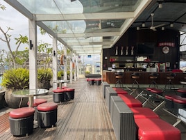 Um bar no terraço com área de estar ao ar livre, balcão e vista para a cidade.