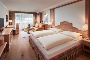Quarto de hotel com uma cama grande, uma escrivaninha com cadeira, um sofá e uma televisão.