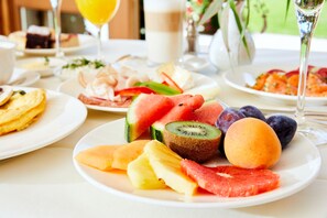 Uma mesa com várias frutas e um copo de suco de laranja.