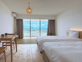 Quarto de hotel com varanda, uma mesa com duas cadeiras e uma cama com cabeceira de madeira.