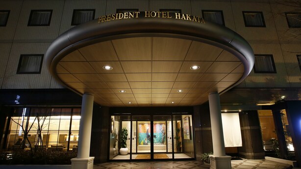 Entrada do Hotel President Hakata com design moderno, apresentando um toldo curvo e piso ladrilhado.