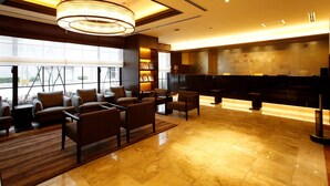Um hall amplo com um piano de cauda, assentos confortáveis e uma mesa de recepção.