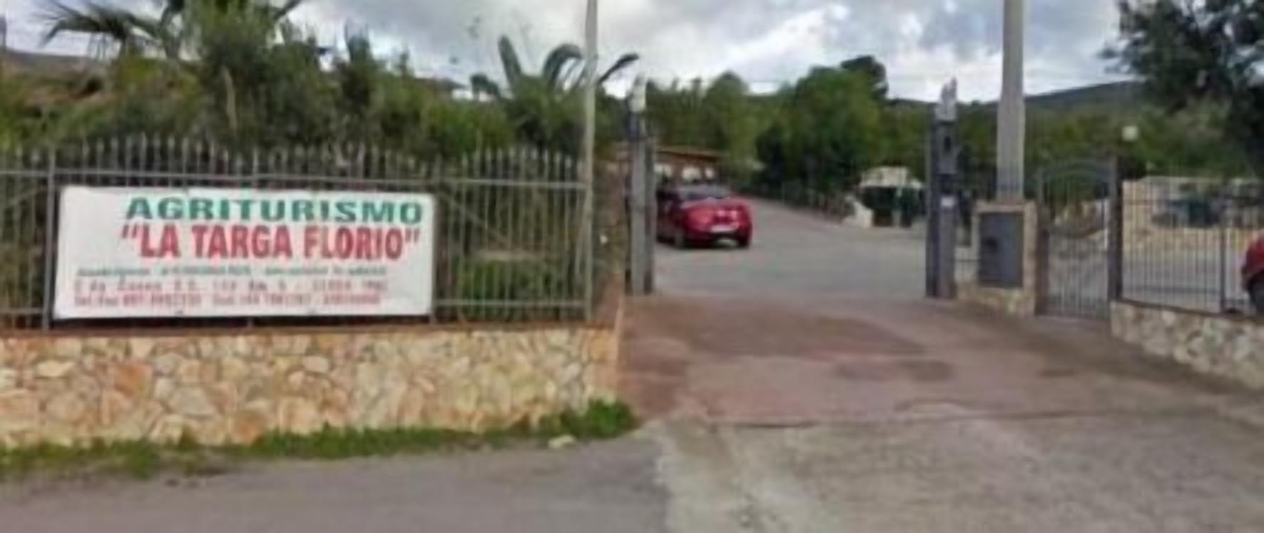 Uma entrada com portão e placa indicando 'Agriturismo La Targa Florio'.