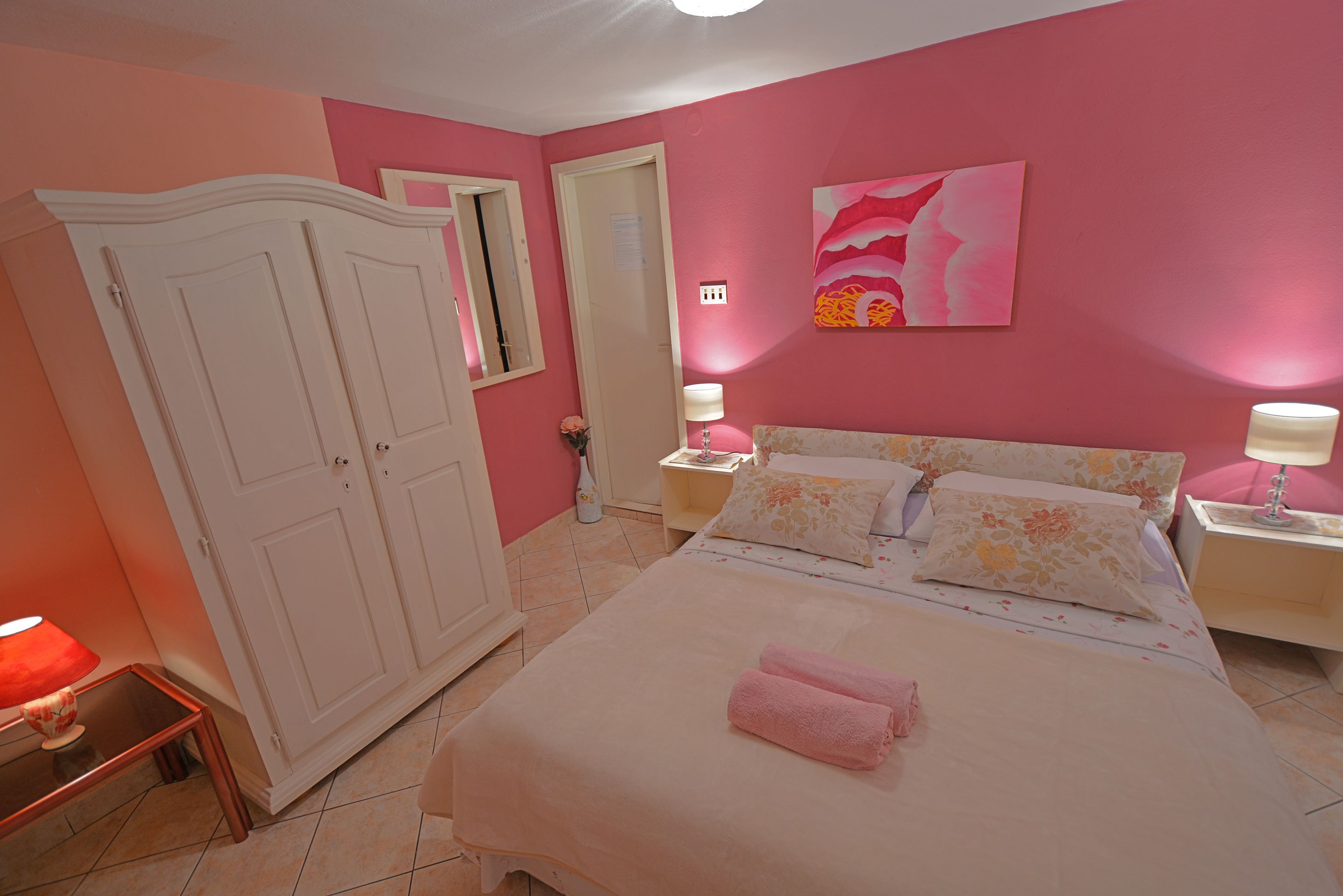 Um quarto com uma cama, mesas de cabeceira, um guarda-roupa e um espelho.